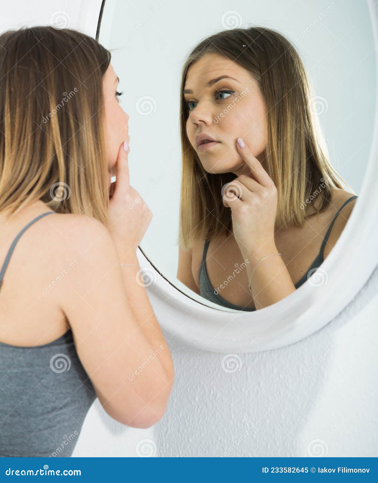 Young Woman Using Mirror and Touching Face in Bedroom Stock Image ...