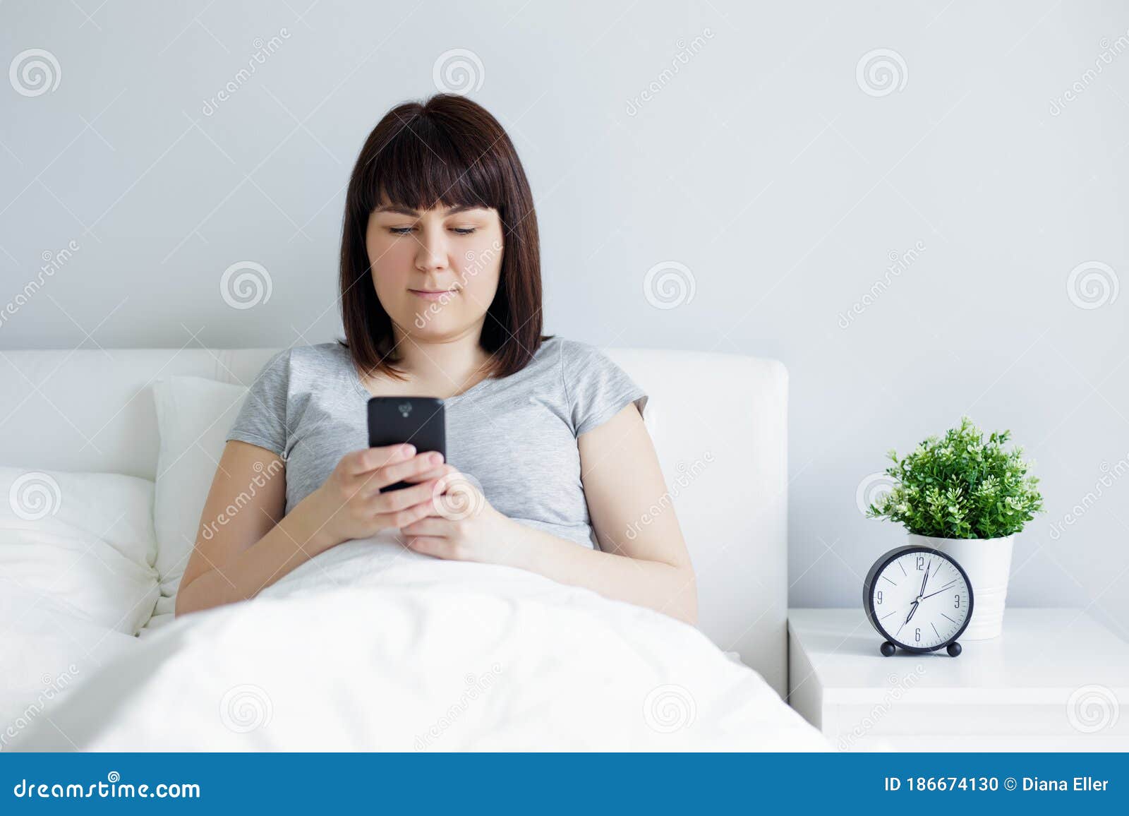 Young Woman Using Smart Phone Lying in Bed at Home Stock Photo - Image ...