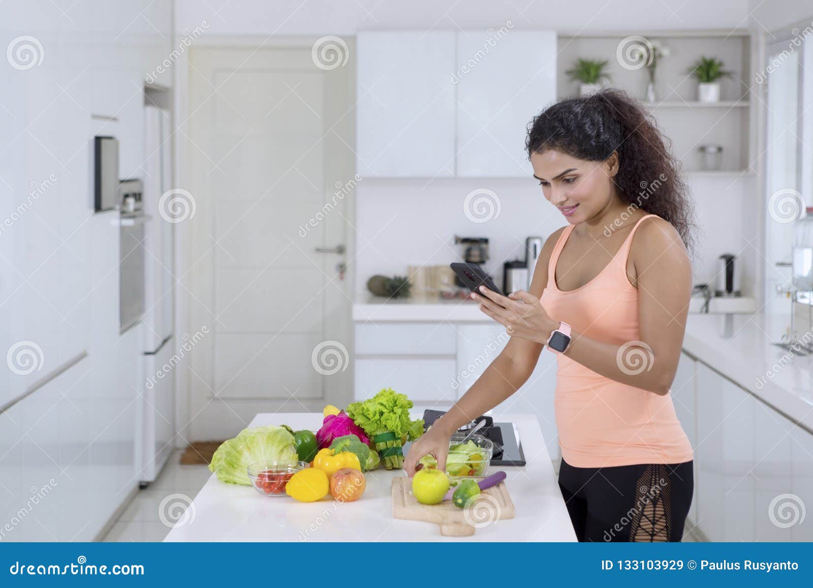 Young Woman Using a Smartphone in the Kitchen Stock Image - Image of ...