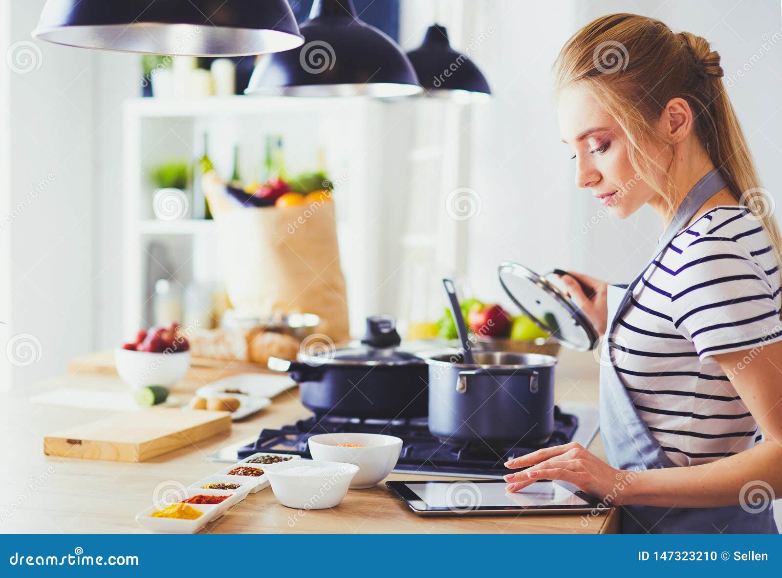 Young Woman Using a Tablet Computer To Cook in Her Kitchen Stock Photo ...