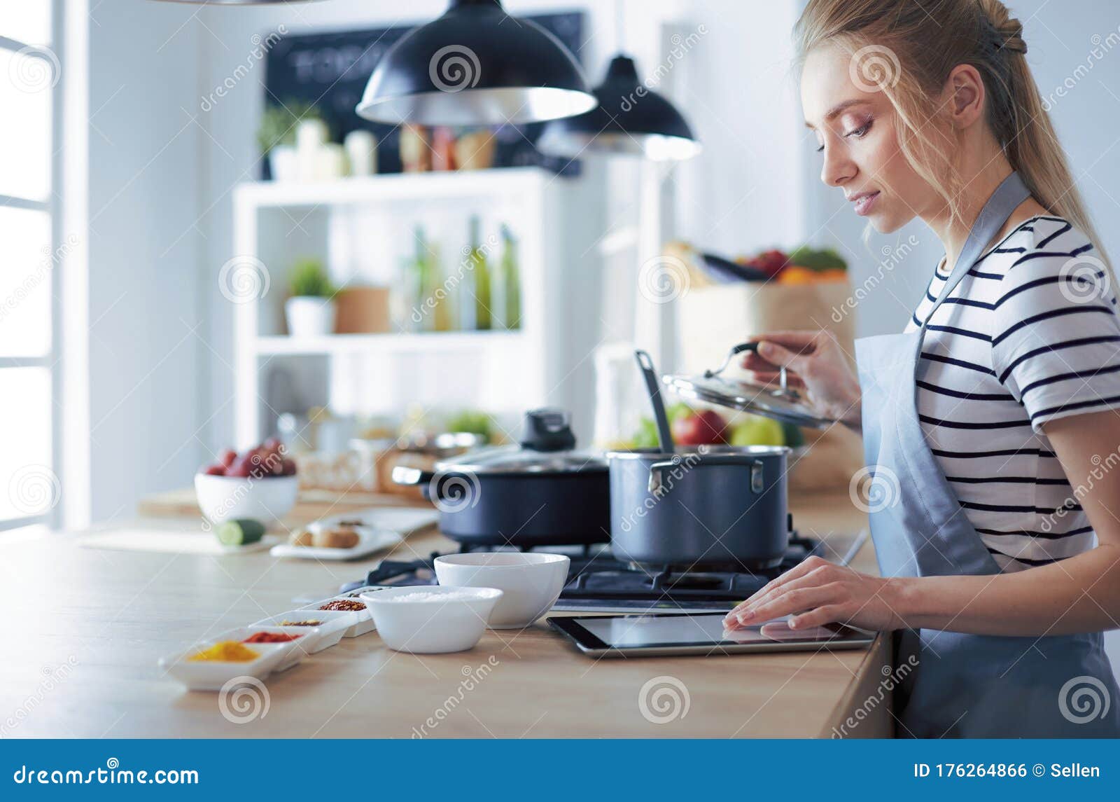 Young Woman Using a Tablet Computer To Cook in Her Kitchen Stock Photo ... Young Woman Using a Tablet Computer To Cook in Her Kitchen Stock Photo ...