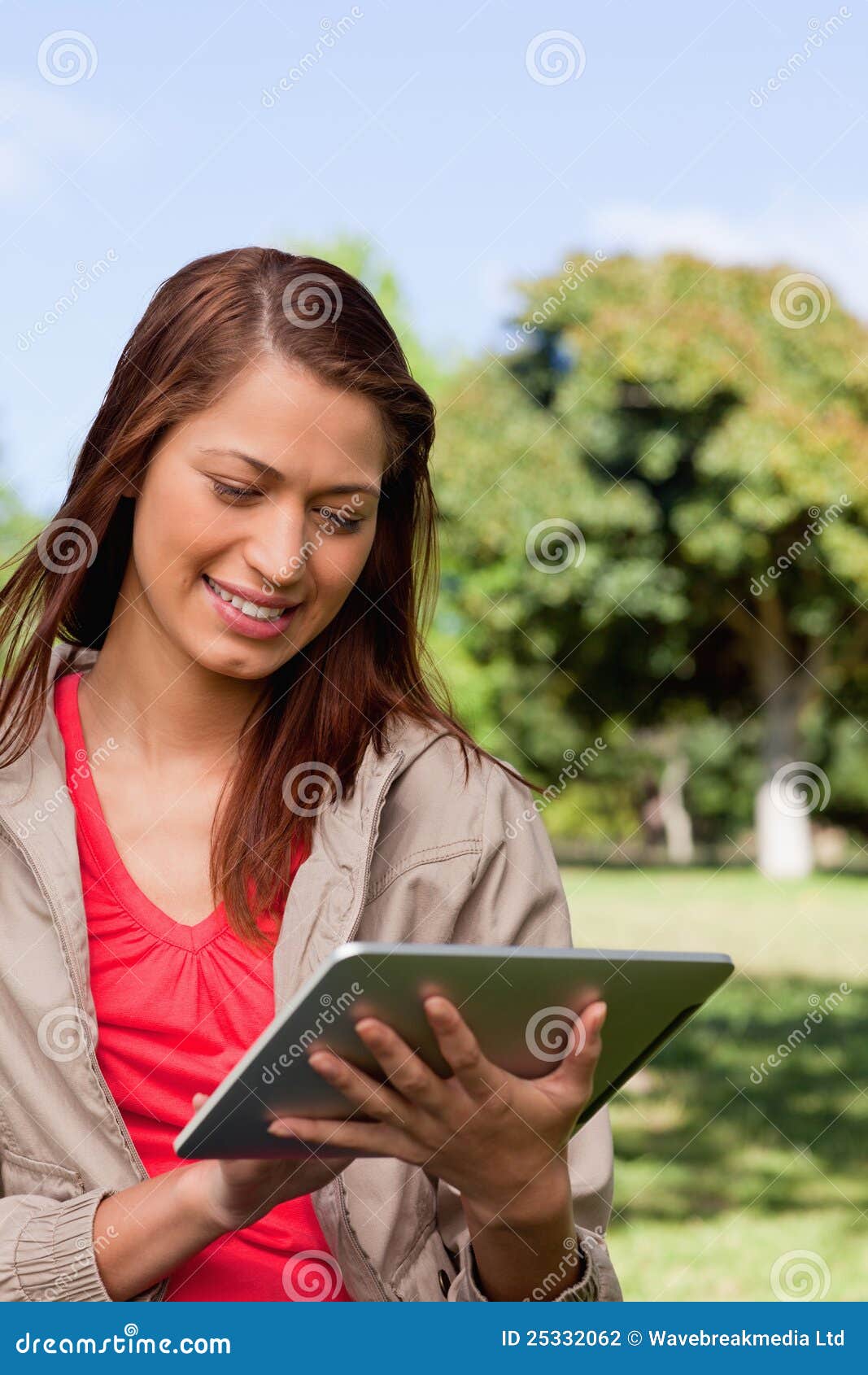 Young Woman Using a Tablet while Standing in Bright Park Stock Photo ...