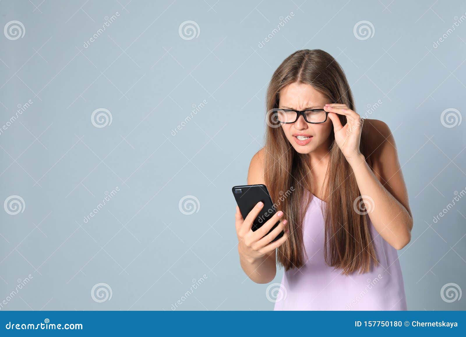 Young Woman with Vision Problems Using Smartphone on Grey Background ...