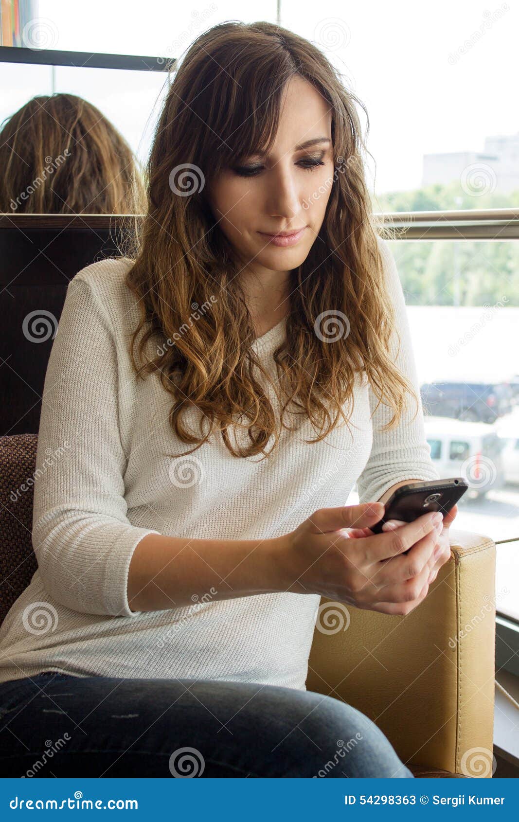 Young Woman Waiting In Restaurant Using Her Smartphone Stock Image