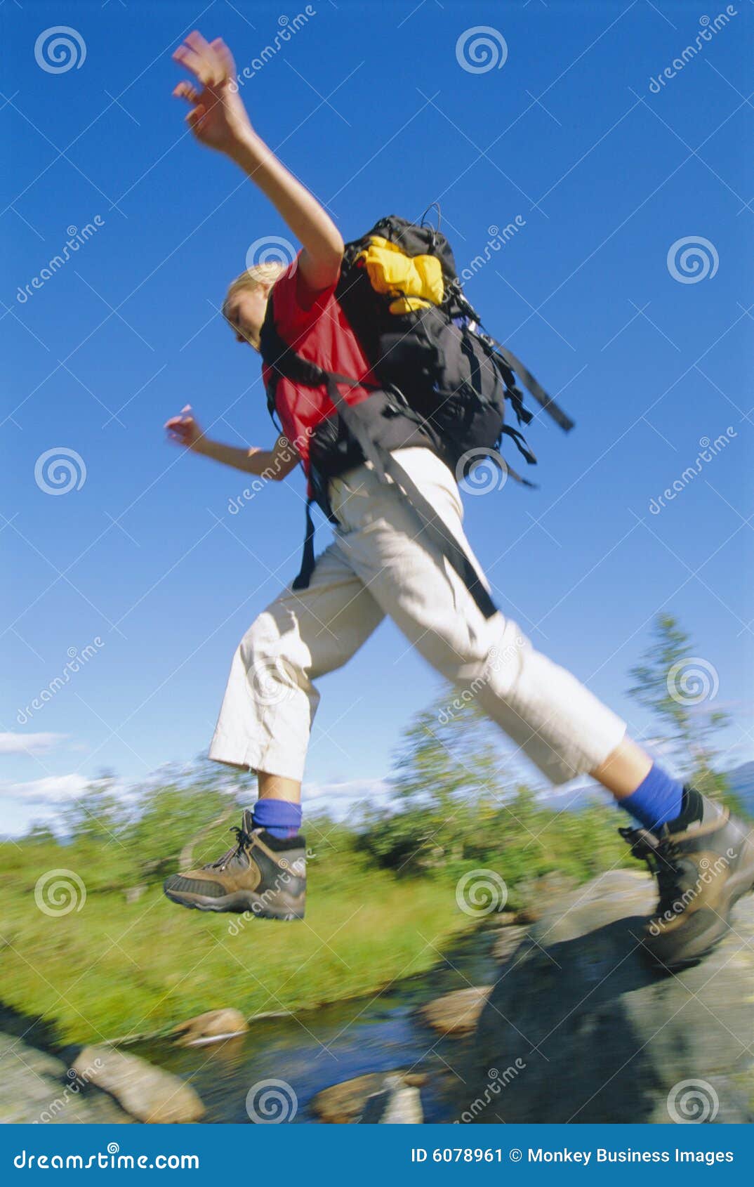 Young Woman Wearing Backpack Leaping Across River Stock Image - Image ...