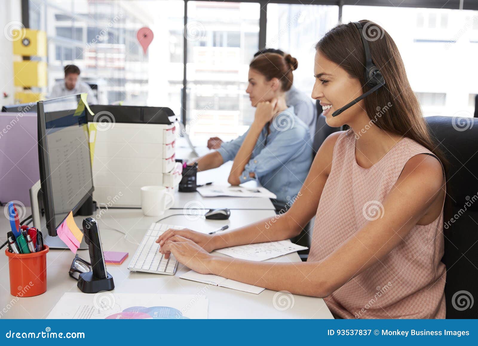 Young Woman Wearing Headset Using Laptop Computer in Office Stock Image ...