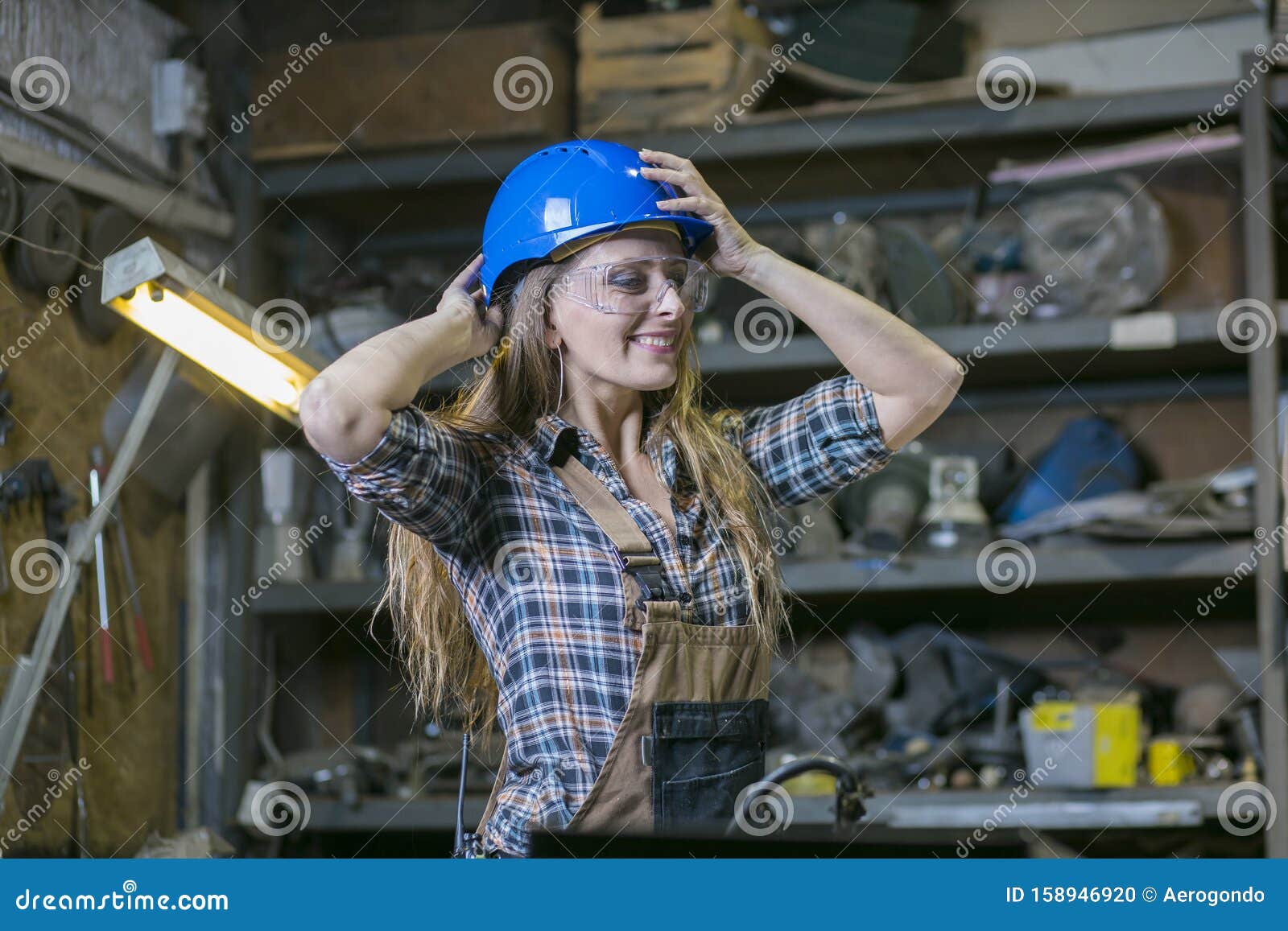 Young Woman in Workshop Putting on Protective Helmet Stock Photo ...
