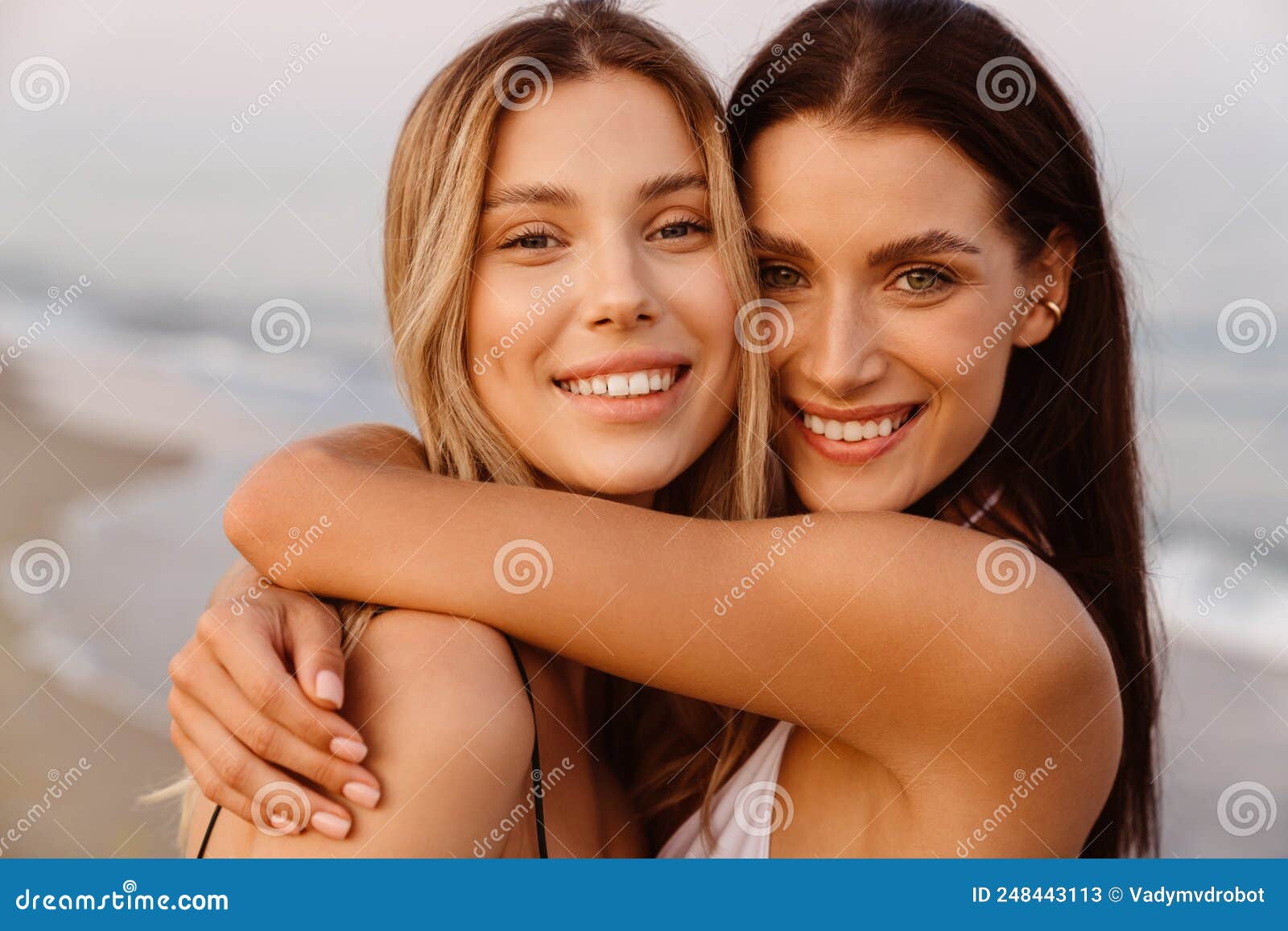 Young Women Hugging and Smiling at Camera on Beach Stock Image - Image ...
