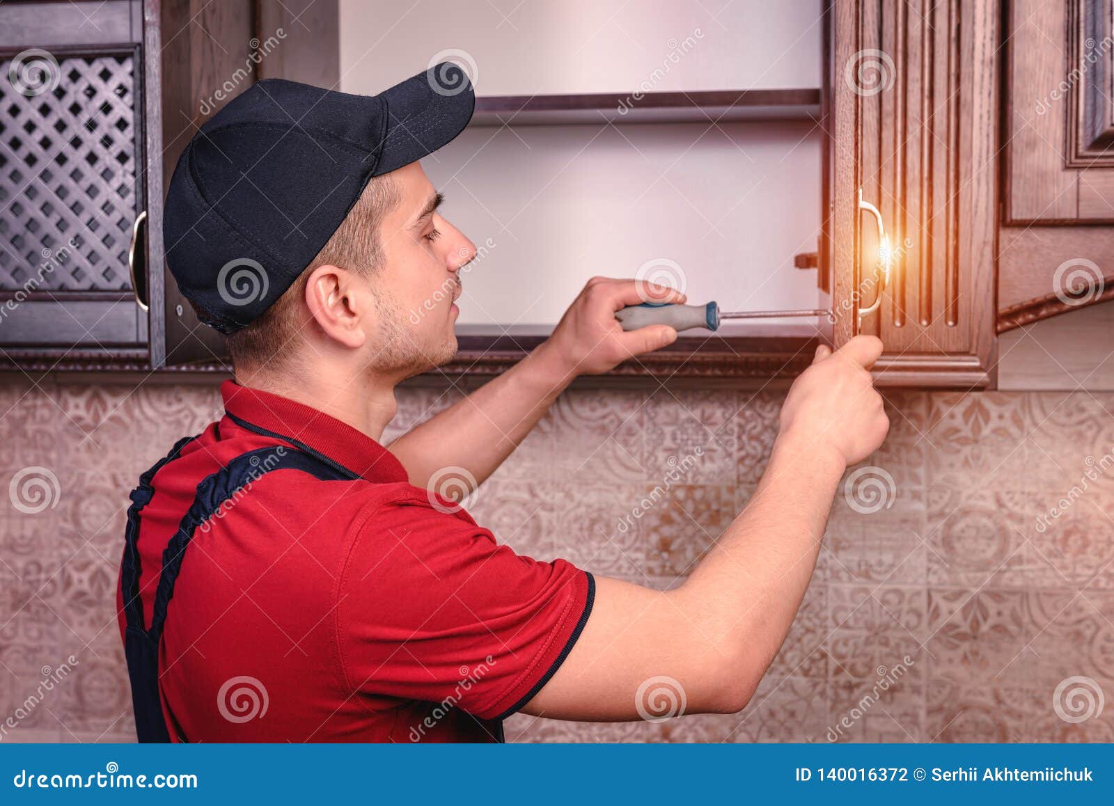 A Young Worker is Assembling Modern Wooden Kitchen Furniture Stock ...