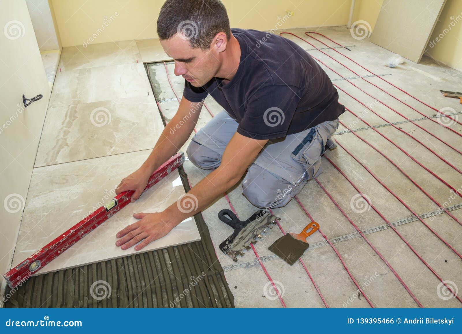 Young Worker Tiler Installing Ceramic Tiles Using Lever on Cement Floor ...
