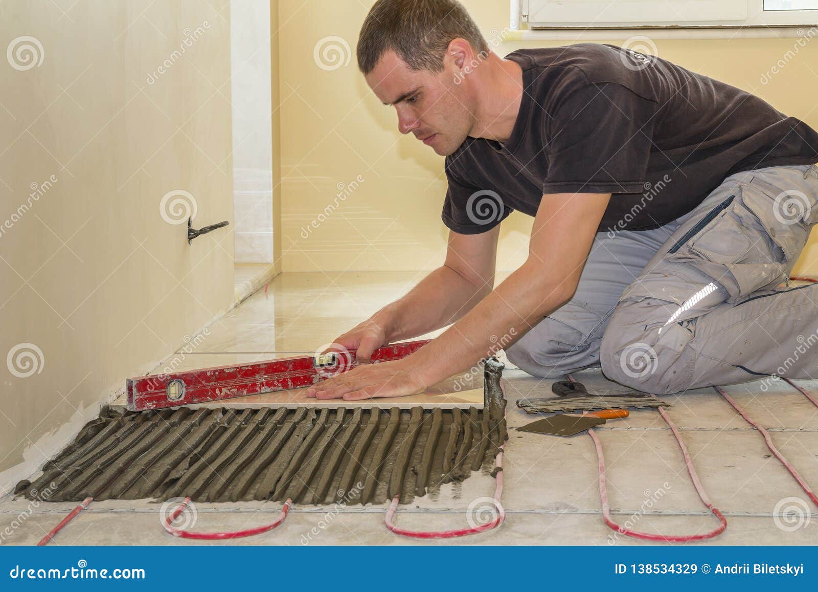 Young Worker Tiler Installing Ceramic Tiles Using Lever on Cement Floor ...