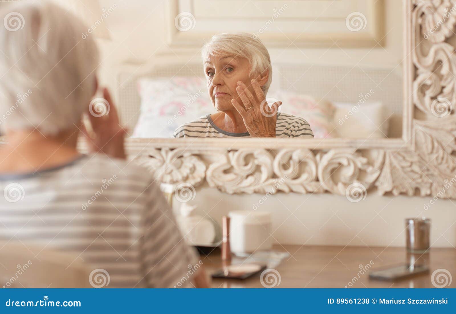 Ältere Frau, Die Ihr Gesicht in Einem Spiegel überprüft Stockfoto ... Ältere Frau, Die Ihr Gesicht in Einem Spiegel überprüft Stockfoto ...
