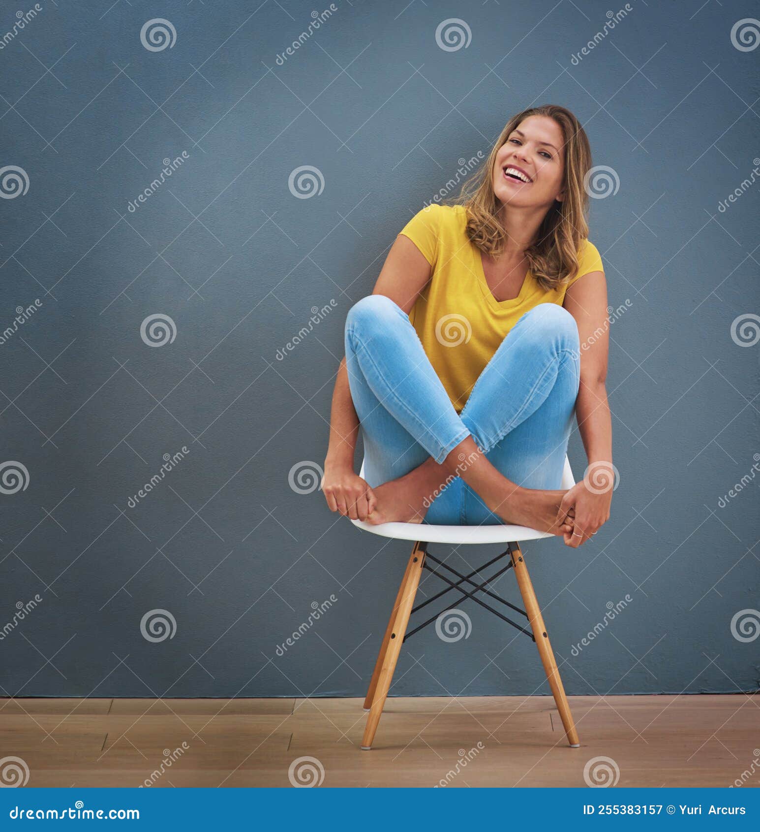 être Heureux Et Sourire Une Jeune Femme Assise Sur Une Chaise Contre