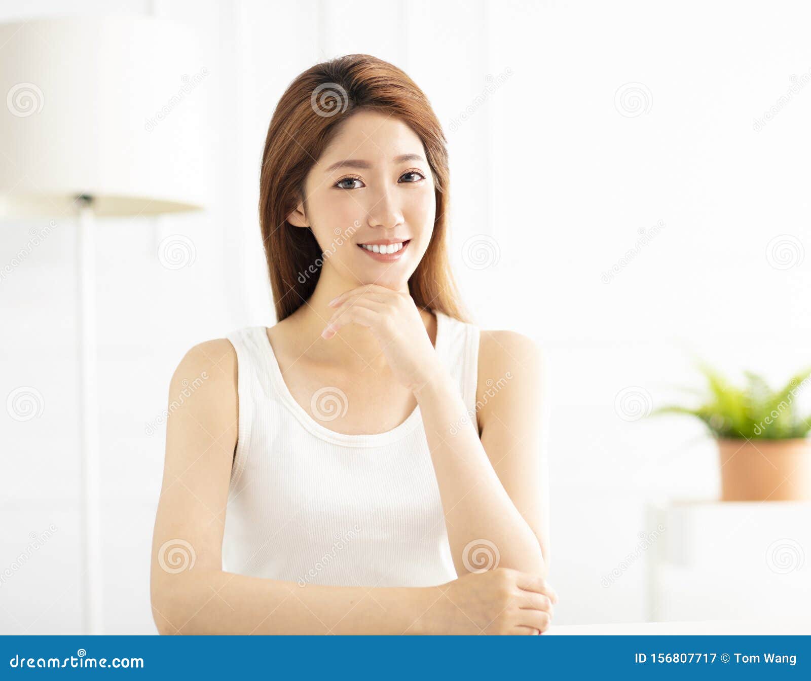 åœ¨å®¢åŽ…é‡Œå¾®ç¬‘ç €çš„å¹´è½äºšæ´²å¥³äººã€‚å®¢åŽ…é‡Œçš„å° ç„ç¬‘ç €çš